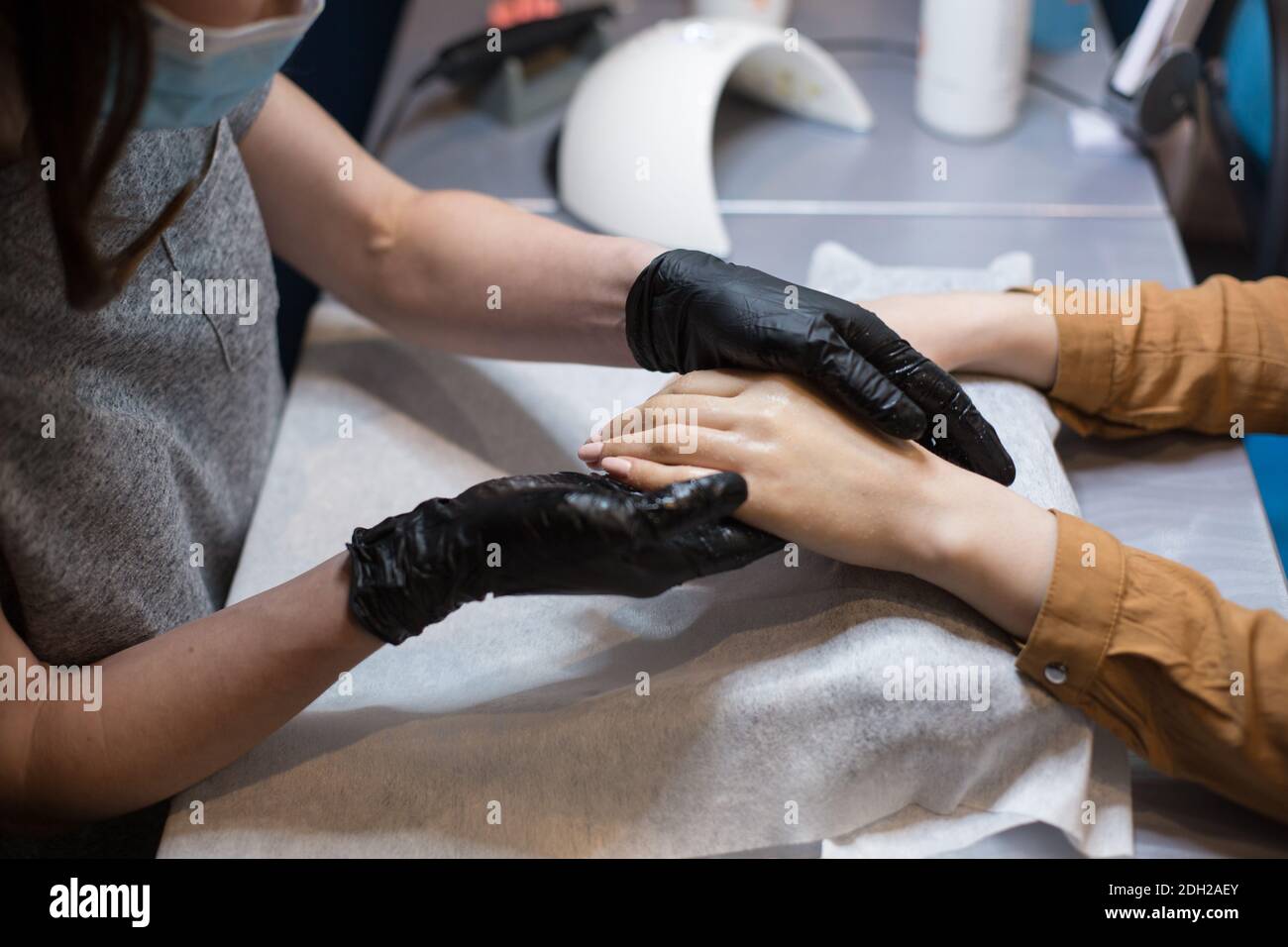 Beauty salon, applying moisturizing cream on client hands and massaging ...