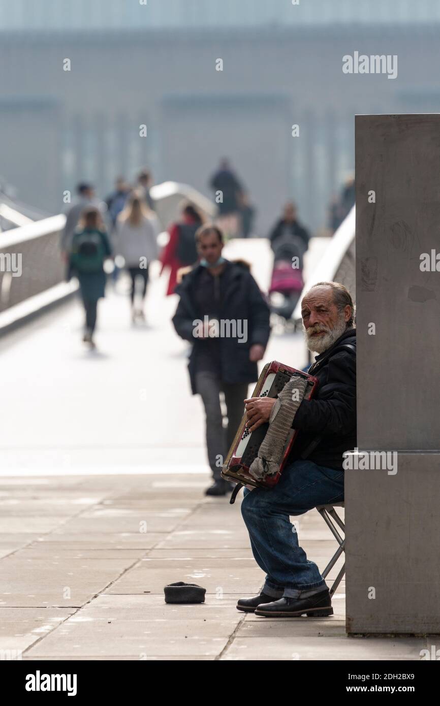 An old man busking on an accordion beside Millennium Bridge, London ...