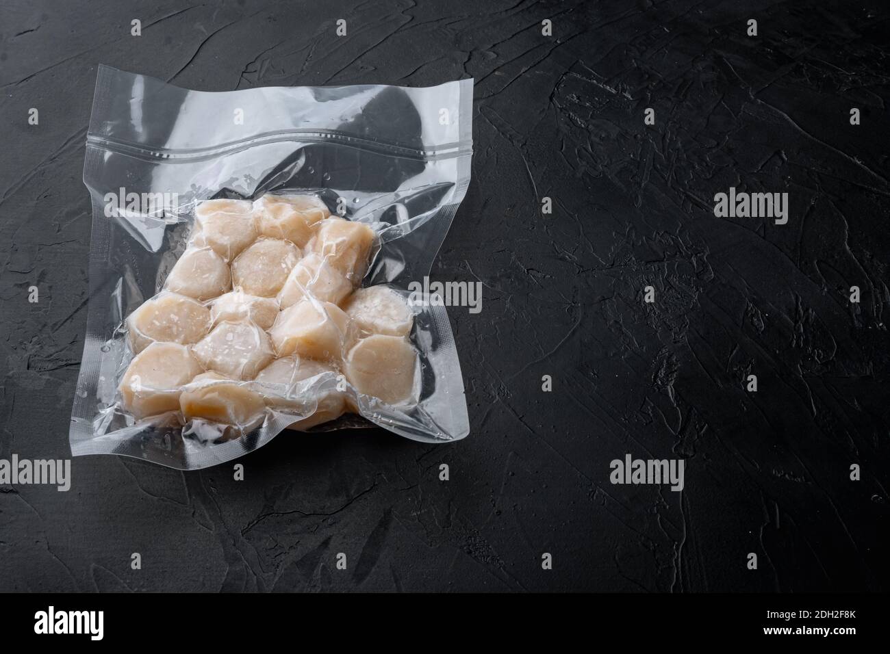Scallops, in vacuum pack, on black textured background with copy space ...