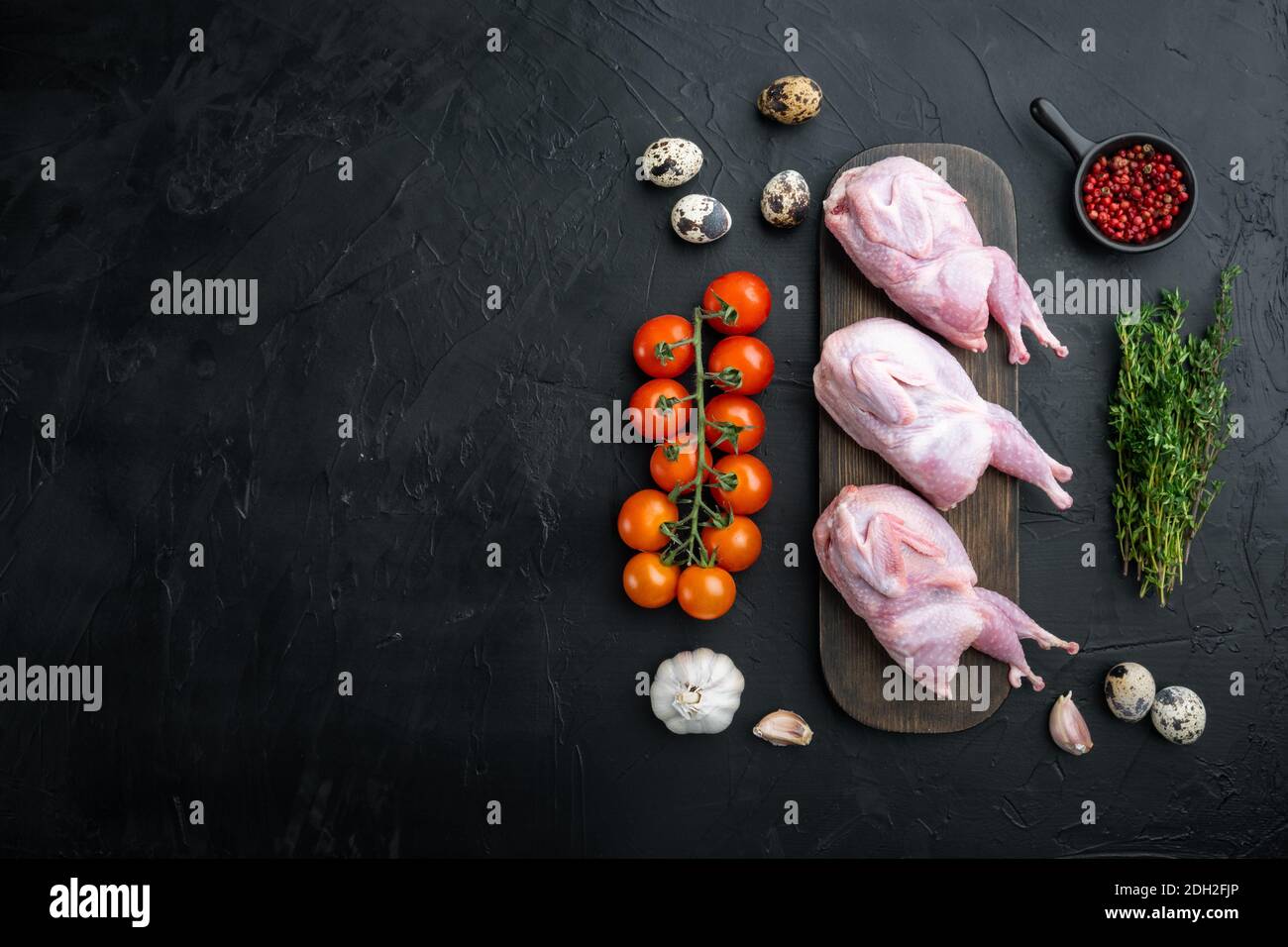 Fresh raw meat quail ready for cooking, flat lay, on black textured ...