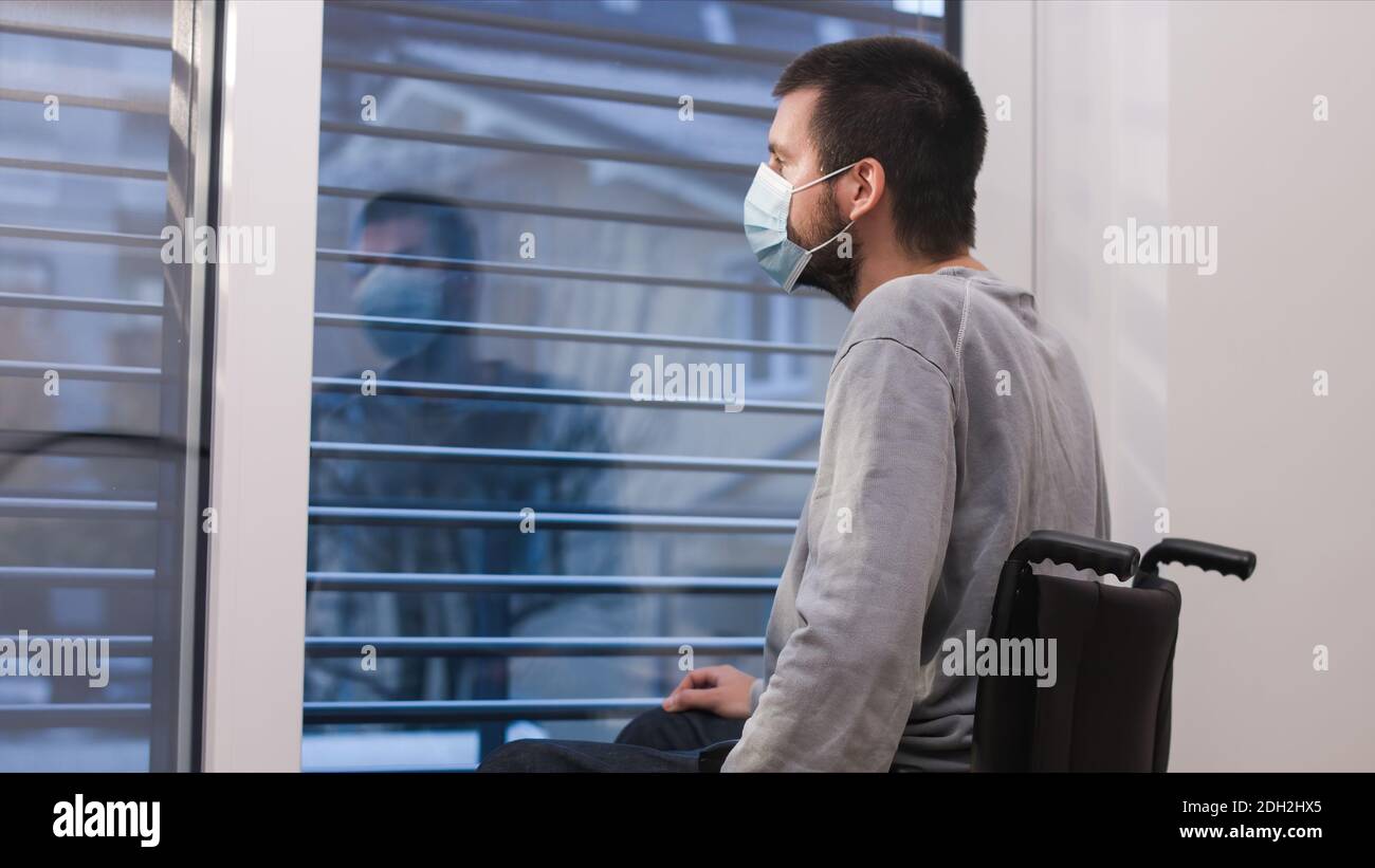 Disabled lonely man wearing face mask sitting in a wheelchair alone ...