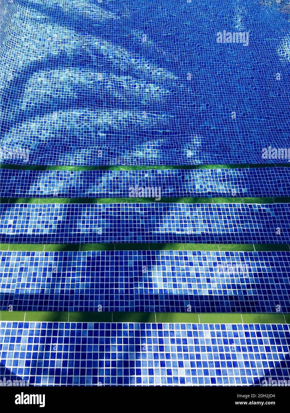 Swimming pool water with ripples, refractions on blue tiled steps, and ...