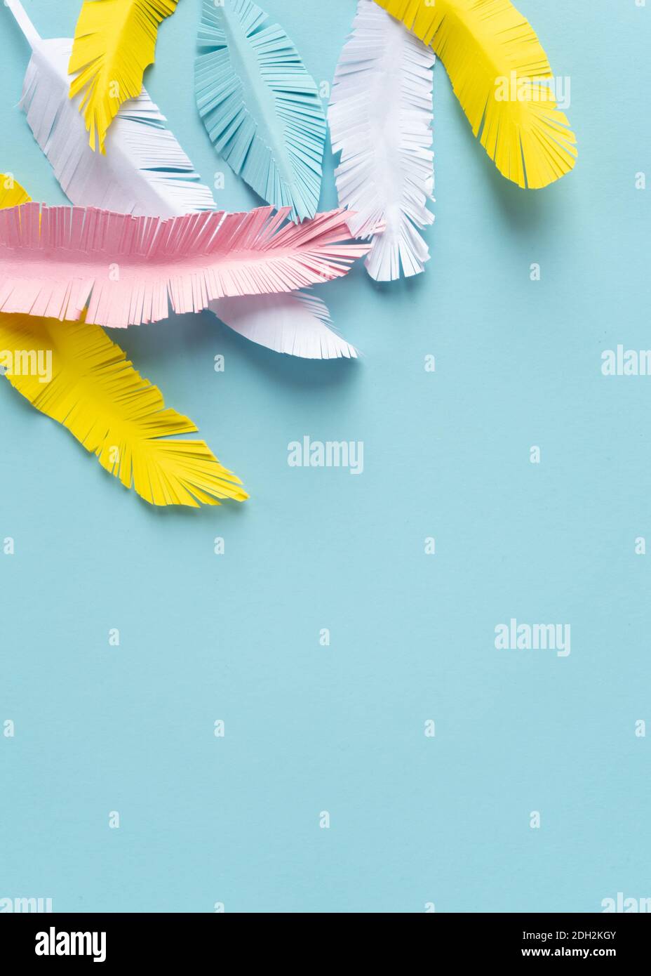 colorful paper feathers on blue background with copy space, vertical ...