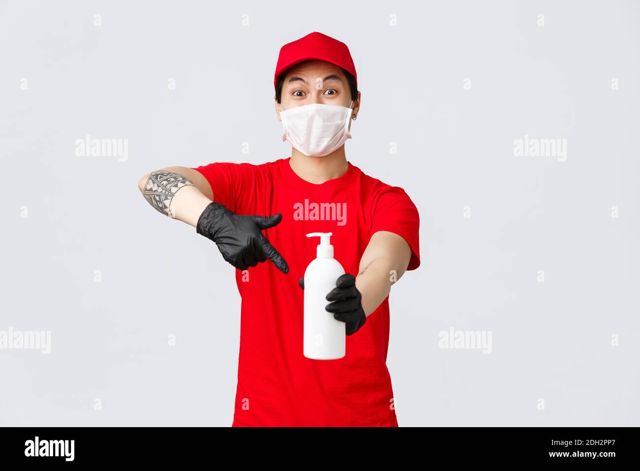Excited delivery guy pointing at hand sanitizer bottle and looking ...