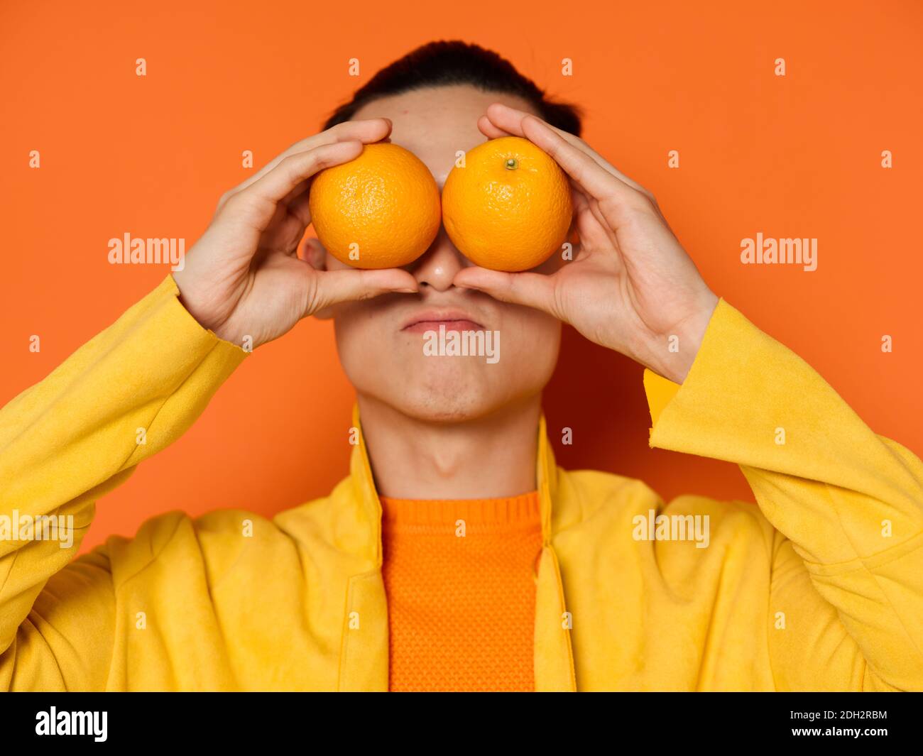 man with orange oranges in hands and emotions yellow jacket isolated ...