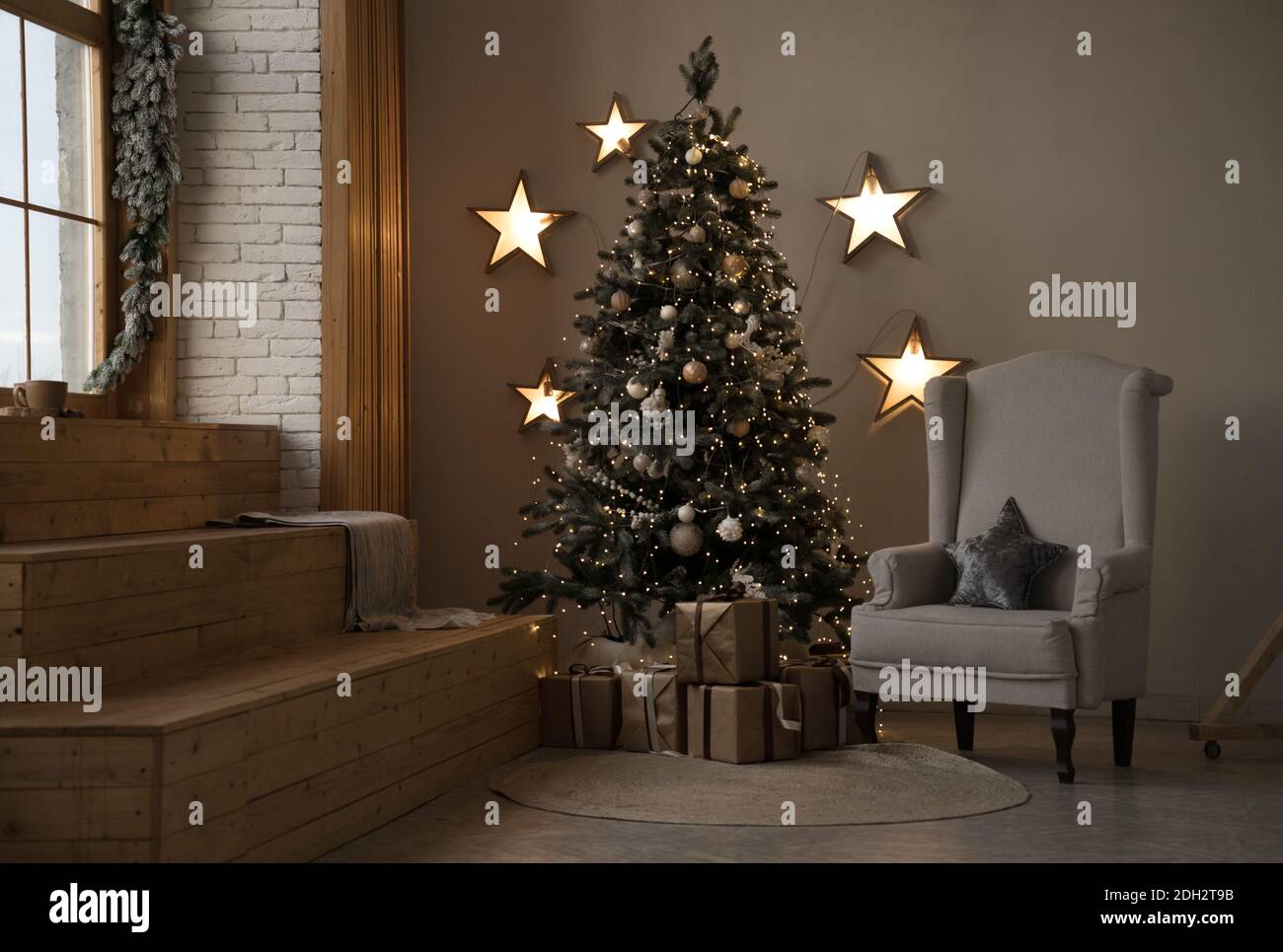 Decorated Christmas tree with gifts and gray armchair Stock Photo - Alamy