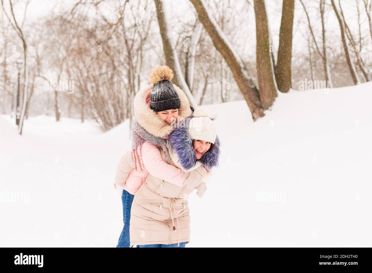 Two girls play snowballs in the winter in the forest. Sisters in a warm ...