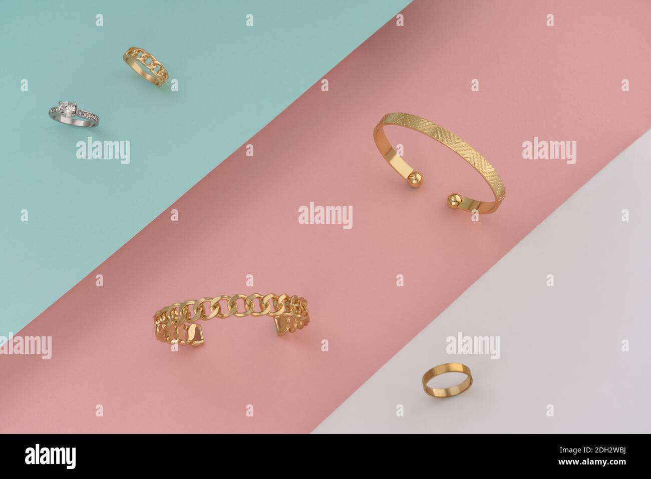 Golden accessories bracelets and rings on pastel colors paper ...
