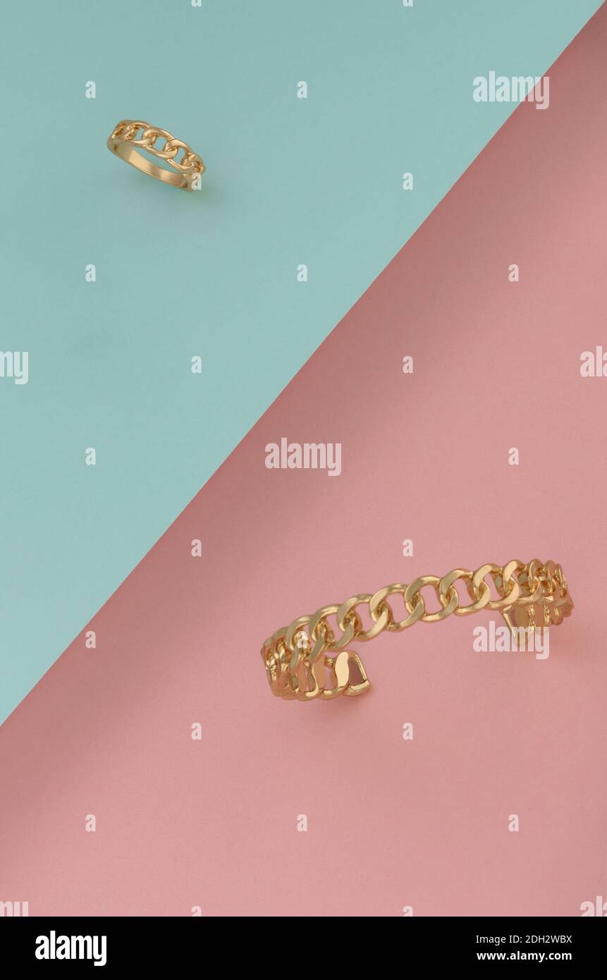 Chain shape golden bracelet and ring on slanted paper background Stock ...