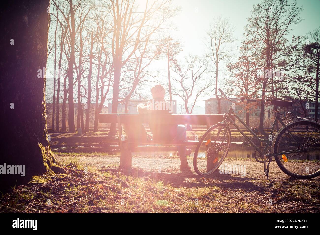 Enjoying the sun in spring: Young girl is sitting on park bench ...