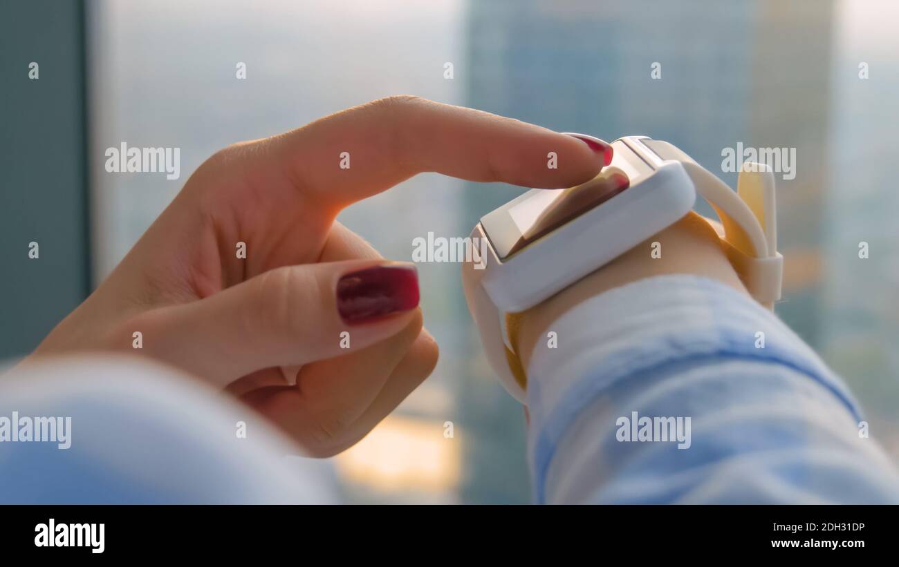 Woman hand using wearable white smart watch in office - close up side ...