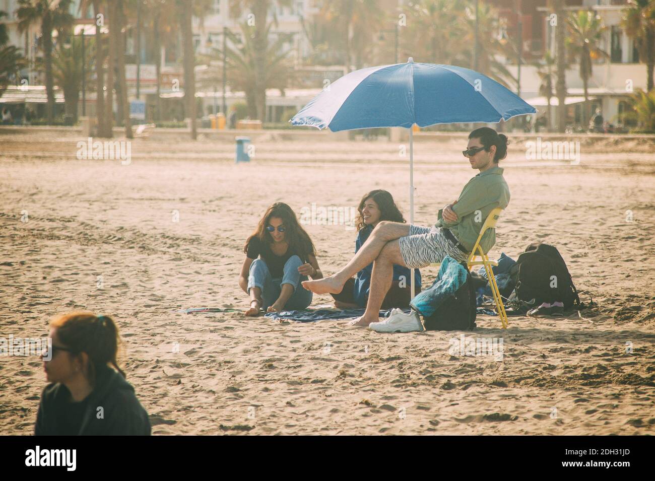 VALENCIA, SPAIN - Nov 21, 2020: Three friend at the beach sunbathing ...