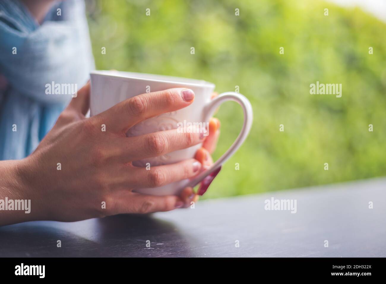 Enjoying a cup of tea: Young girl is sitting on the veranda, holding a ...