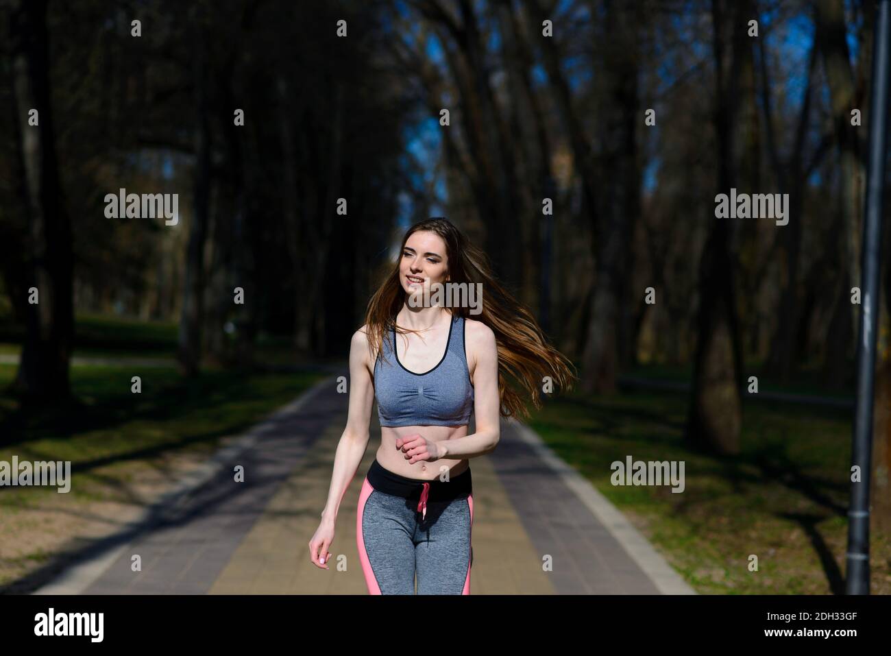 A close up of attractive young woman running, doing fitness outdoors ...