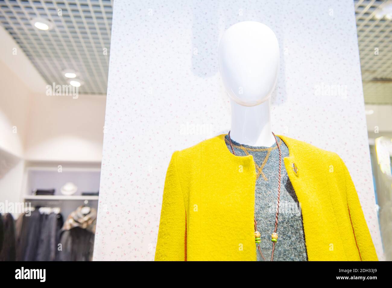 Female mannequin in the bright yellow coat and grey top on the showcase ...