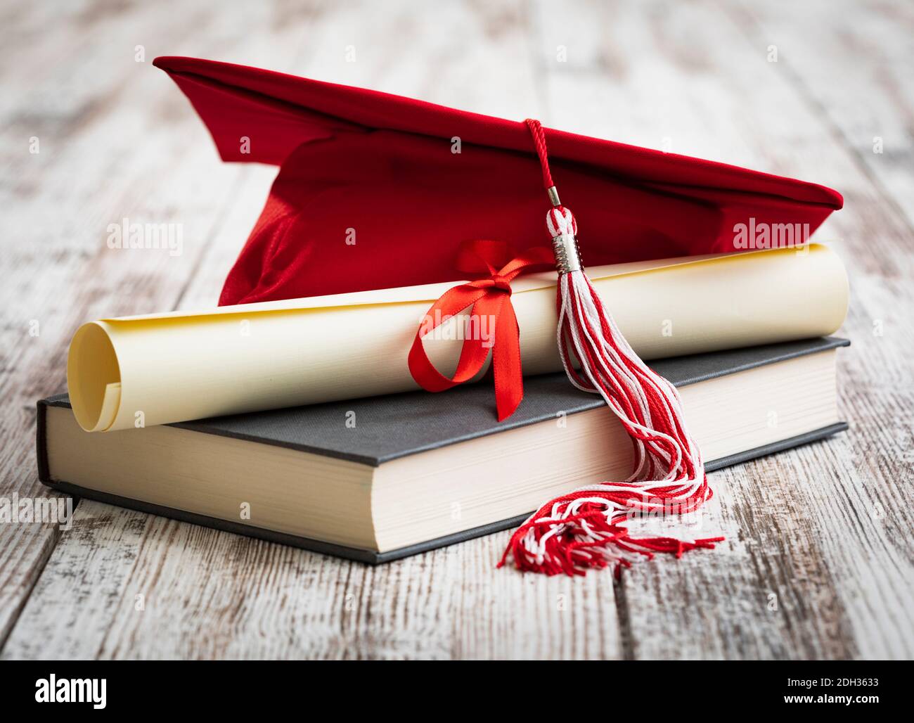 Graduation cap and diploma placed on top of a stack of books on a ...