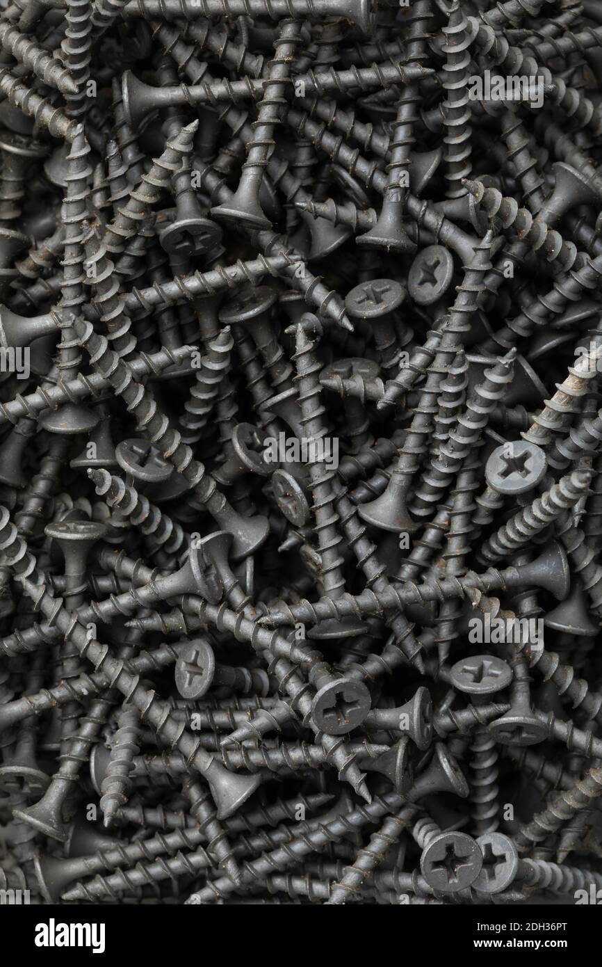 Collection of black screws scattered across a flat surface in a ...