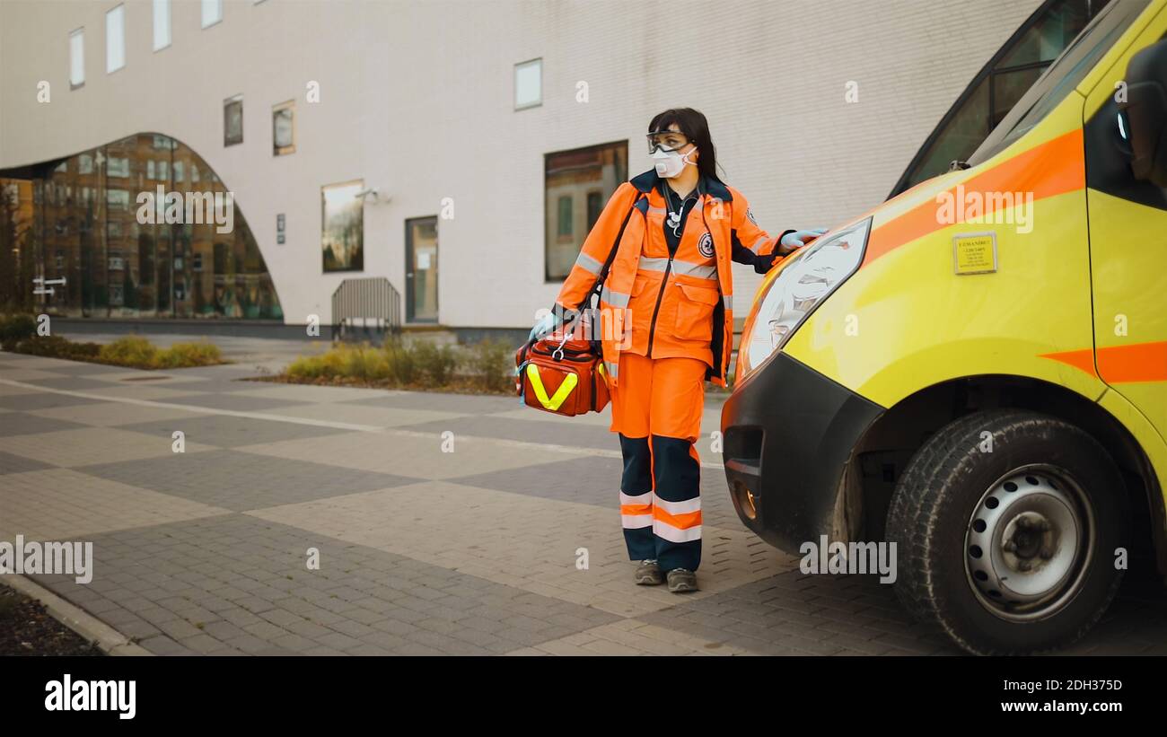 Establishing shot: Paramedic stands near ambulance. Writing on clothes ...