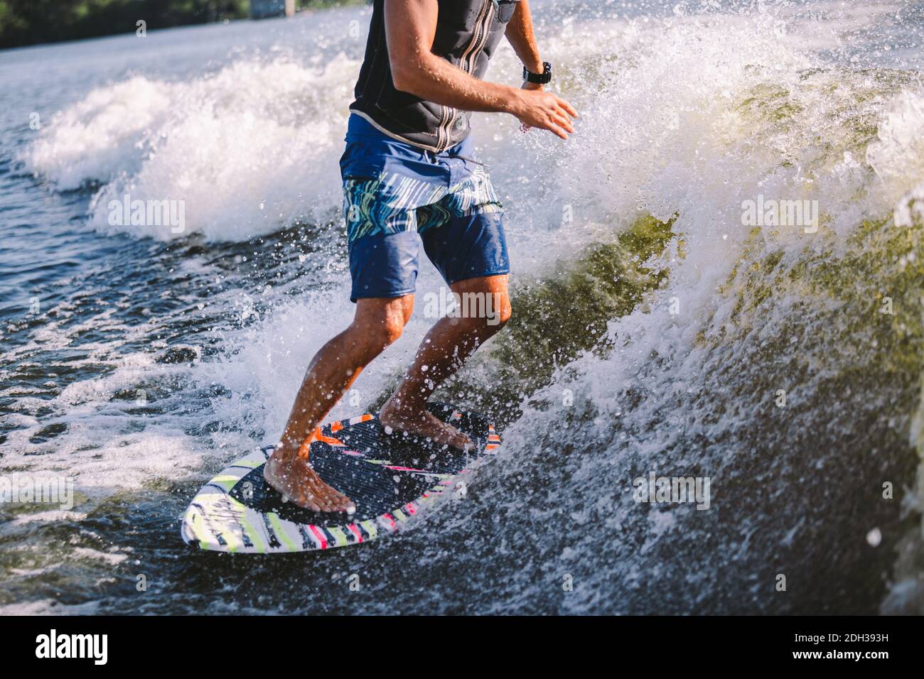 Active wakesurfer jumping on wake board down the river waves. Surfer on ...
