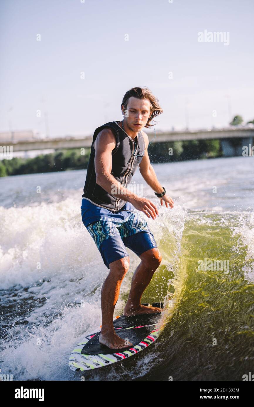 Active wakesurfer jumping on wake board down the river waves. Surfer on ...