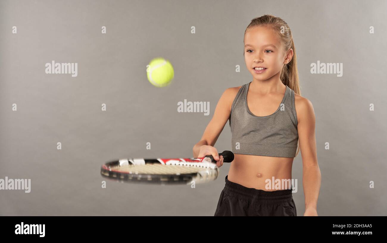 Cute female child in sportswear playing tennis and smiling while ...