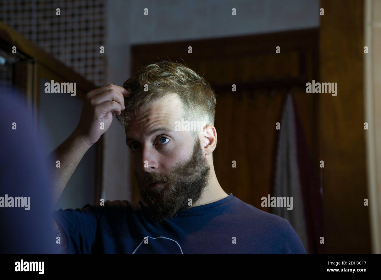 man observing and taking care of himself in front of the bathroom ...