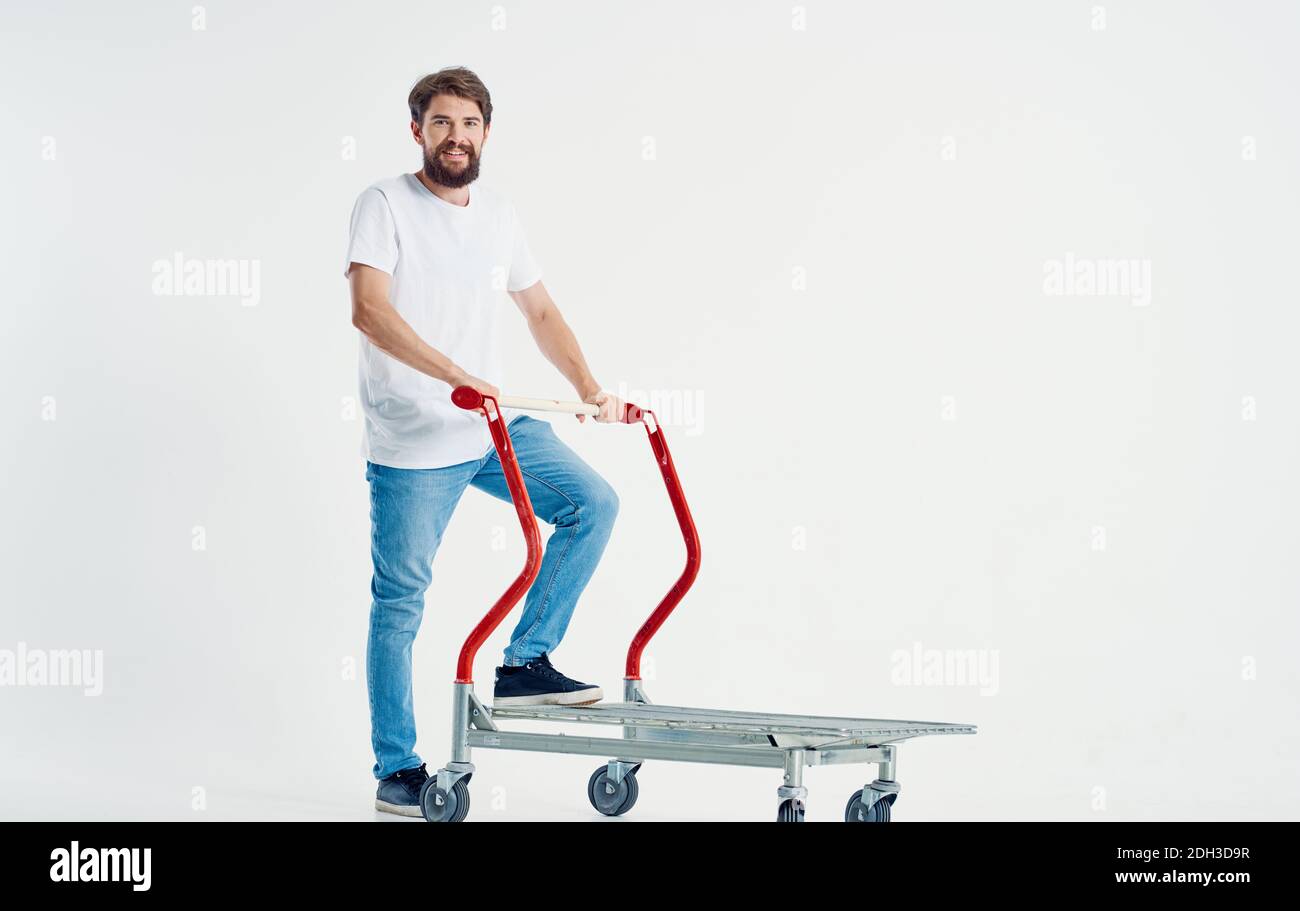 man with a trolley in his hand on a light background transporting heavy ...