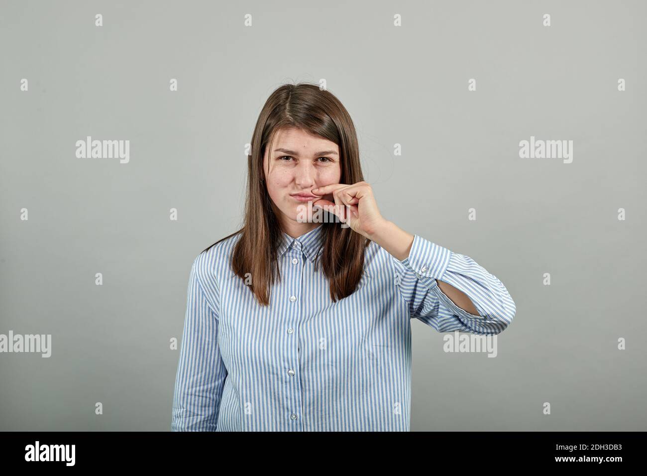 Person showing zip gesture as if shutting mouth on key. Keeping your ...