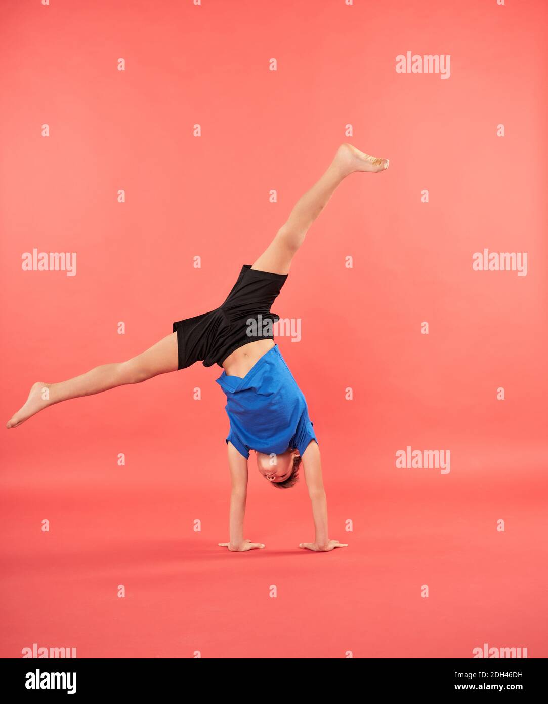 Adorable male child in sportswear standing upside down and doing splits ...