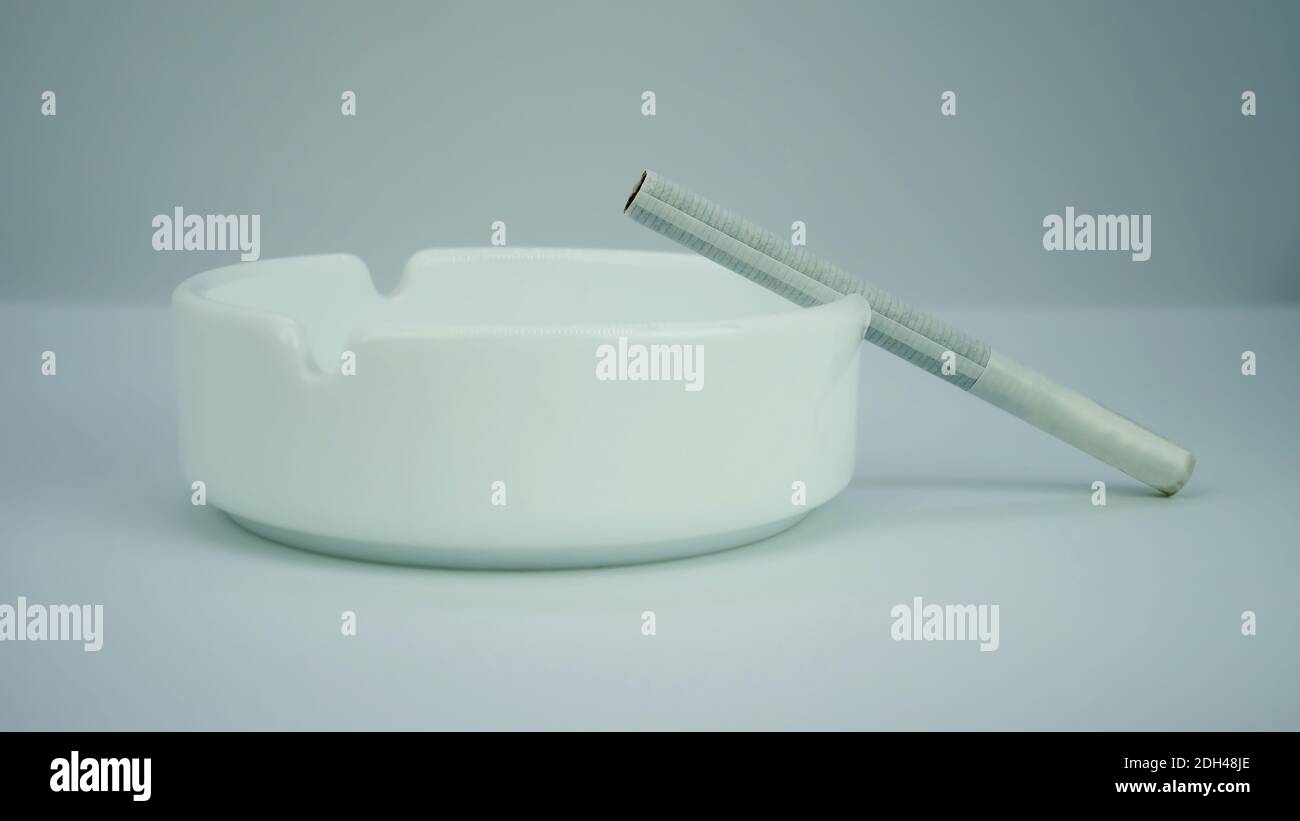 White ashtray with a cigarette on a white background Stock Photo - Alamy