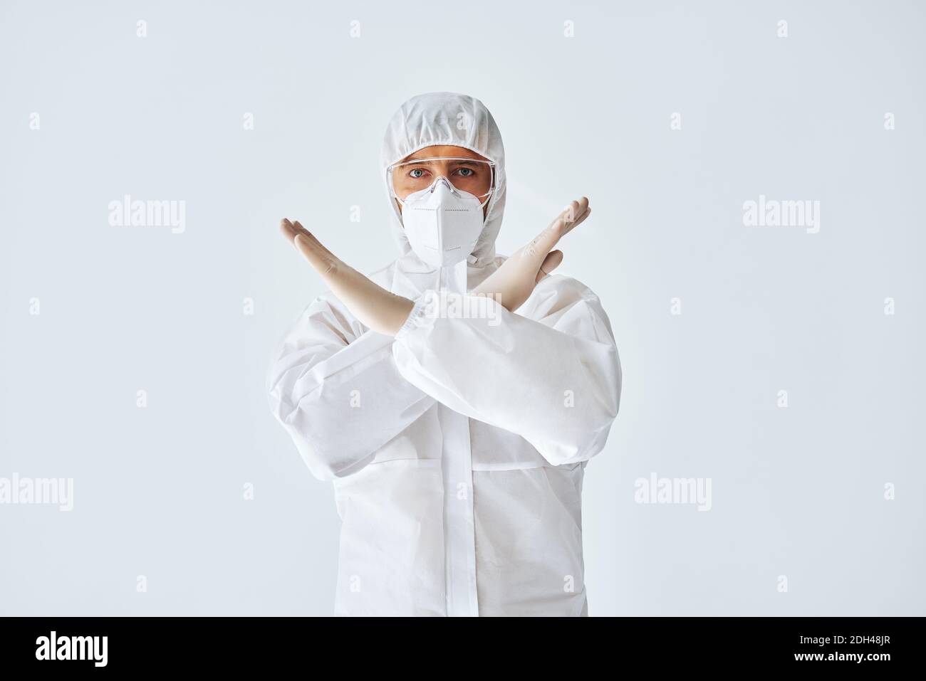 Doctor in protective medical suit showing stop sign on white background ...