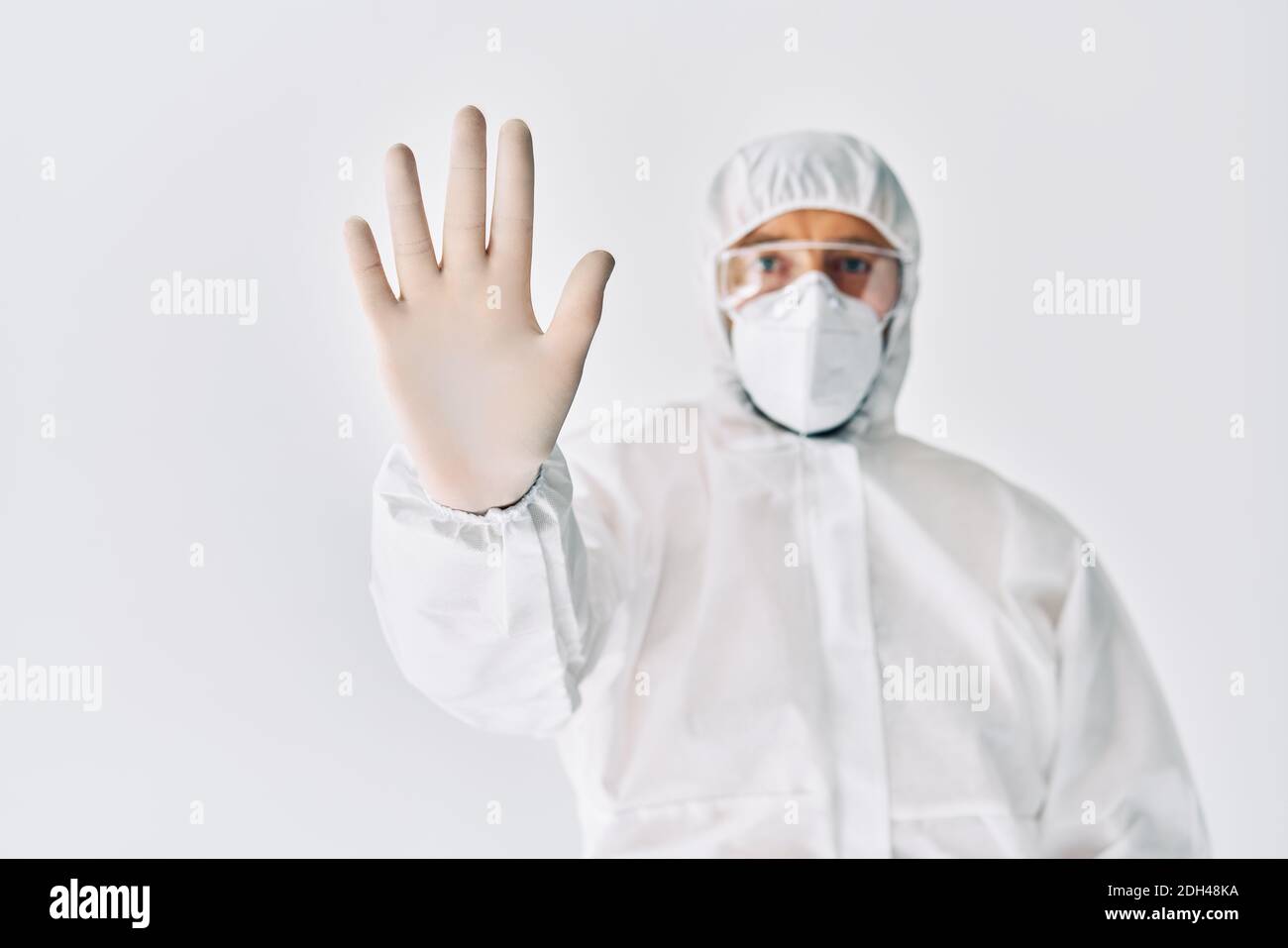 Doctor in protective medical suit showing stop sign on white background ...