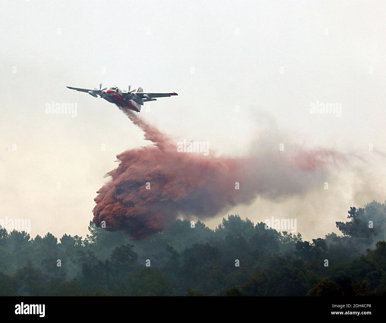 A fire fighting aircraft drops water over a fire in Sainte-Cezaire-sur ...