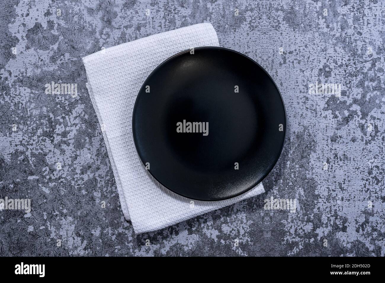Black plate, cutlery and napkin on rustic stone table top view. Table ...