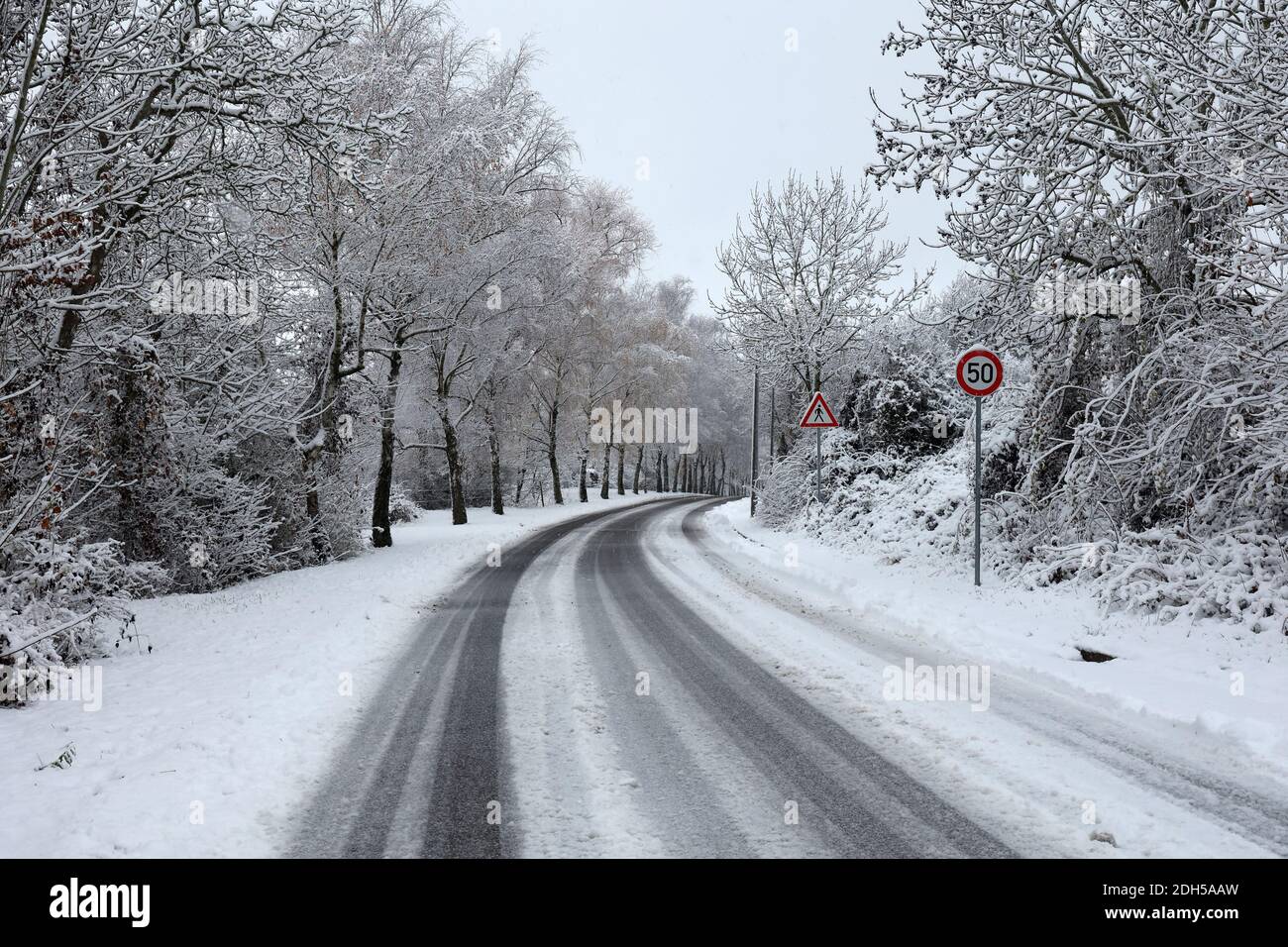 A winding slippery and snowy road surrounded by trees covered in snow ...