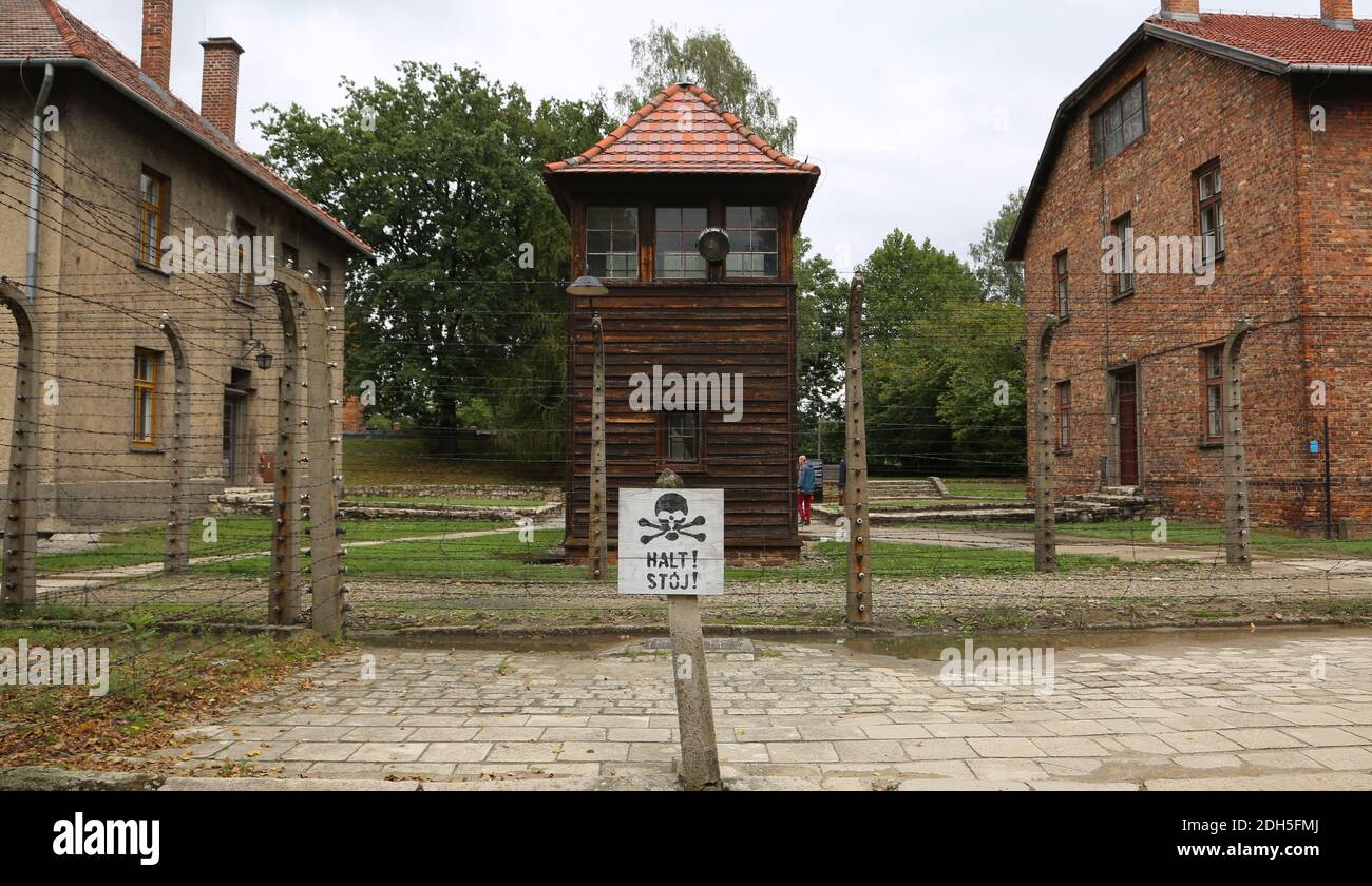 A guard tower and barracks surrounded by barbed wire fences at the ...