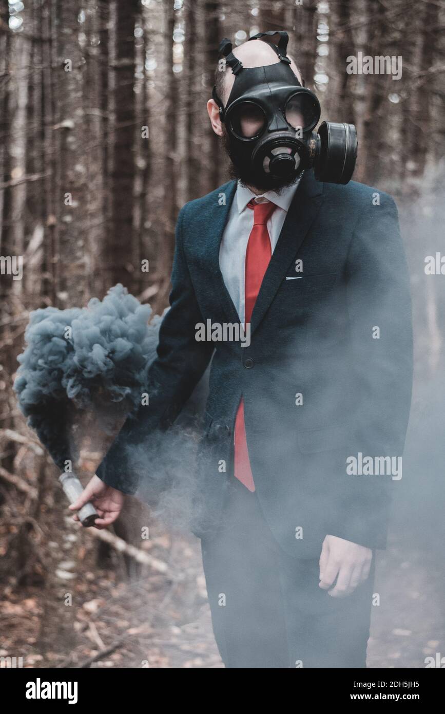 man wearing a business suit and gas mask with a smoke grenade in the ...