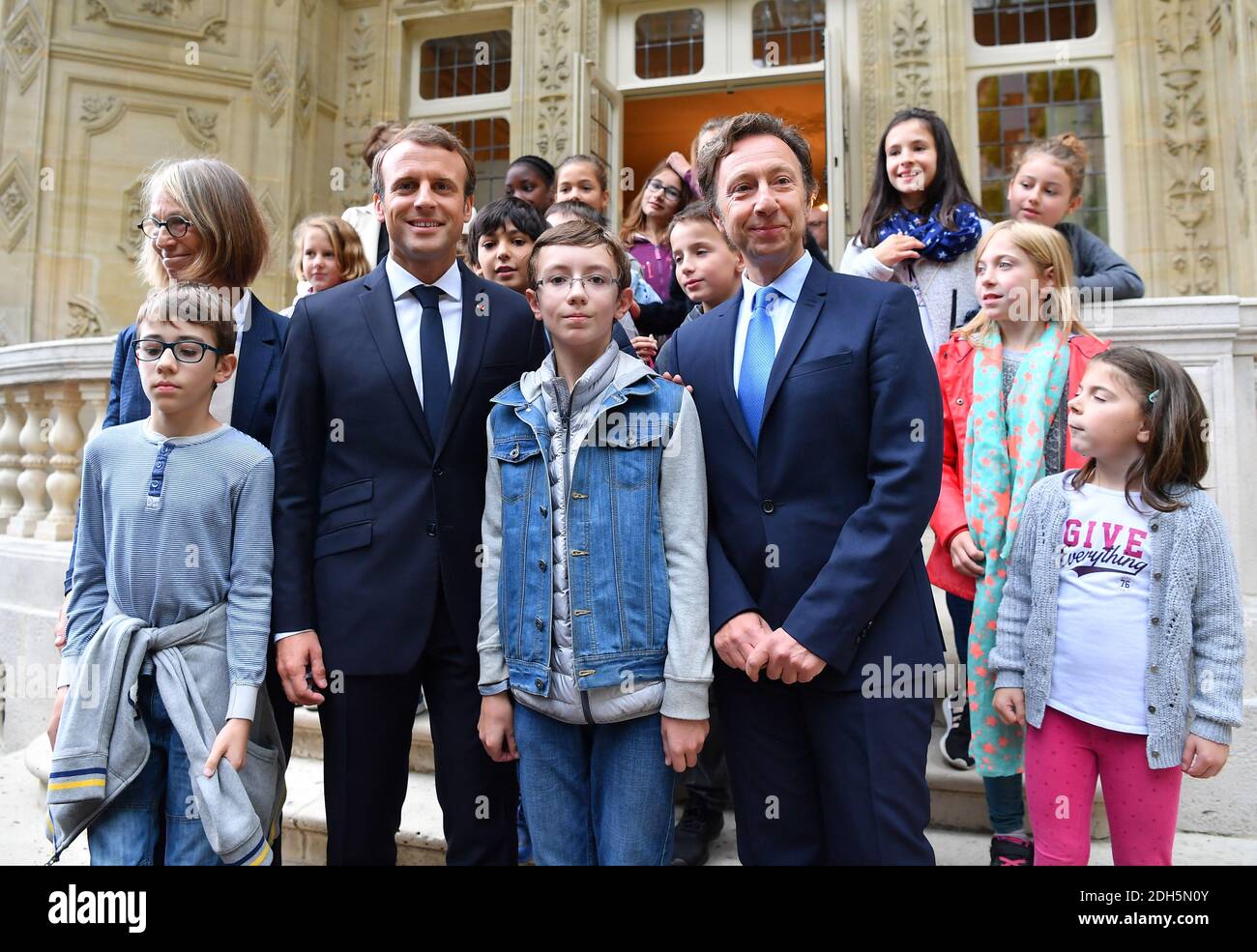 French President Emmanuel Macron (R) shakes hands with television host ...