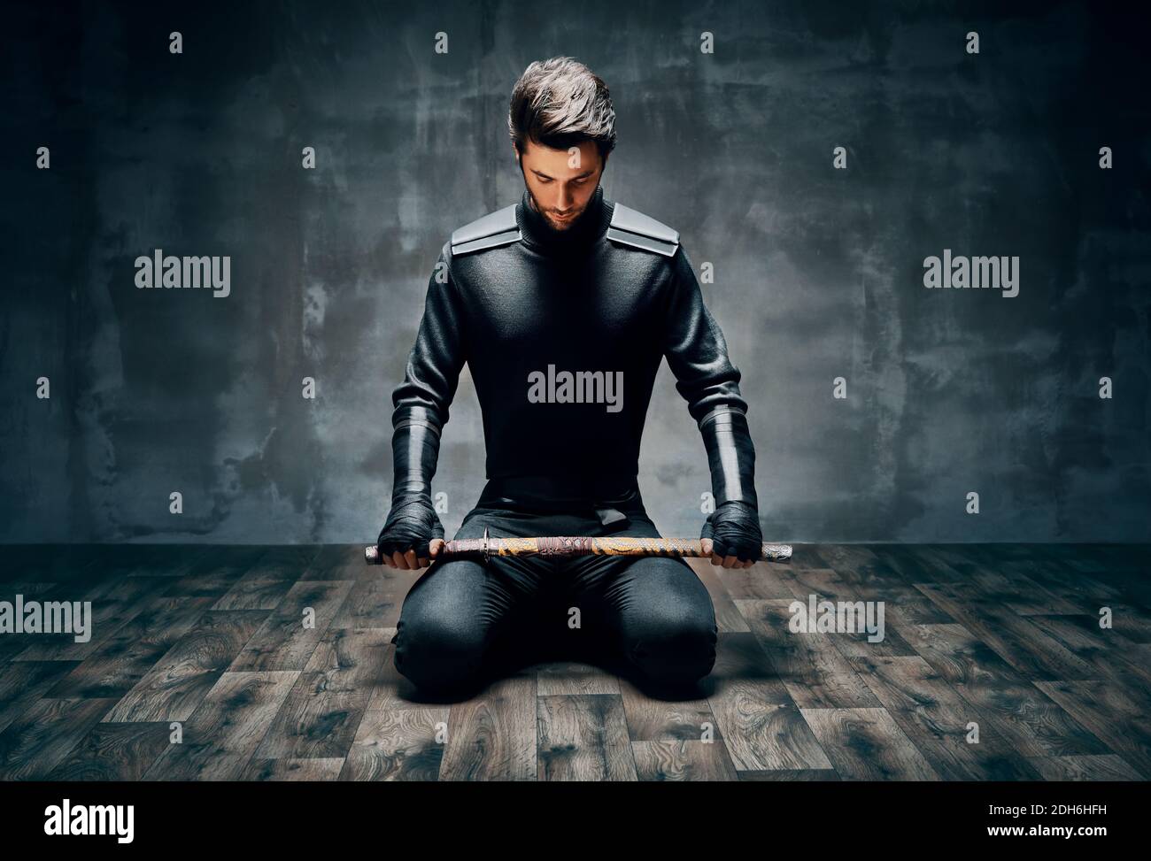 Warrior man sitting on floor posing with a sword Stock Photo - Alamy