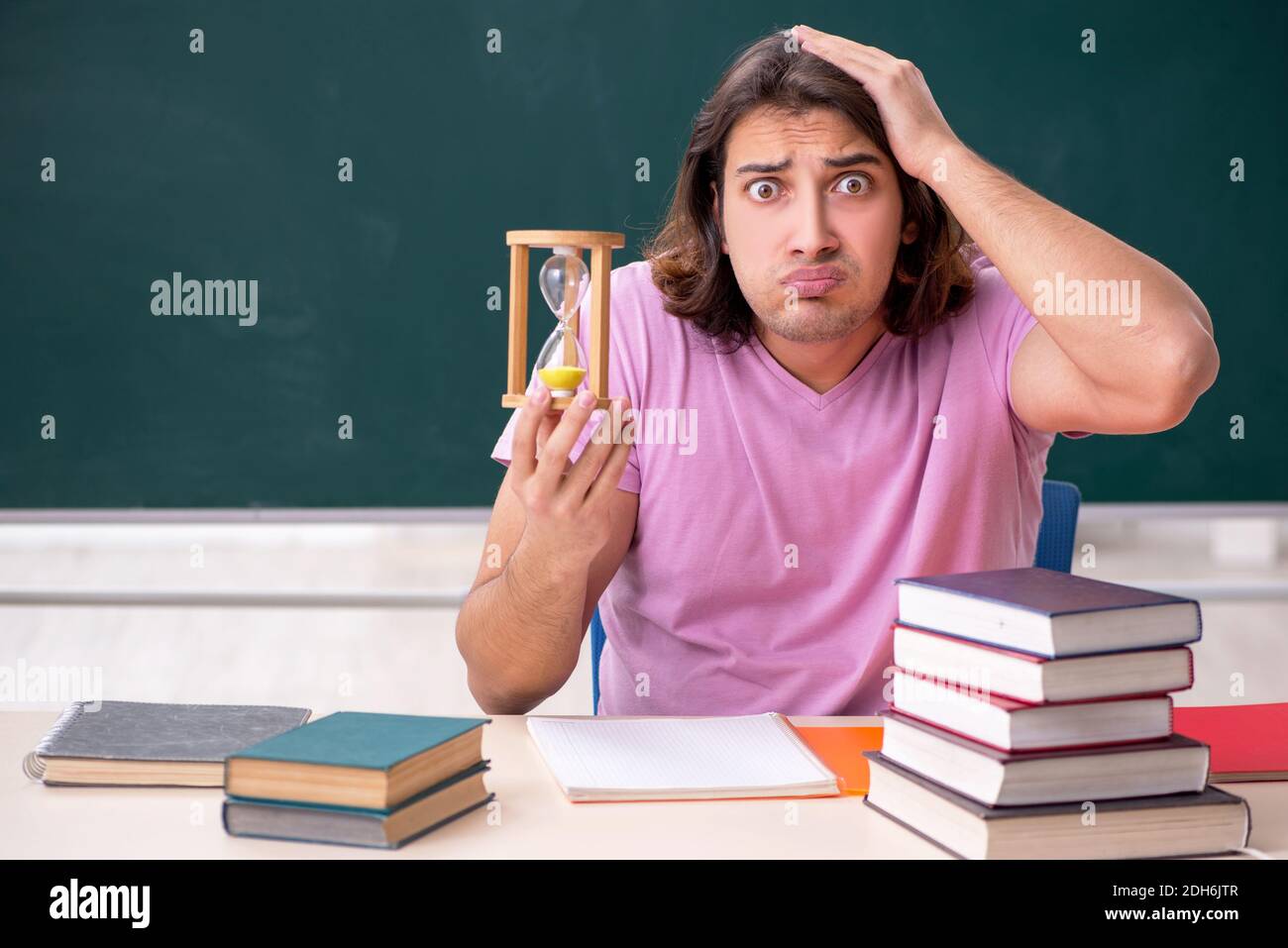 Young male student in the classroom at time management concept Stock ...