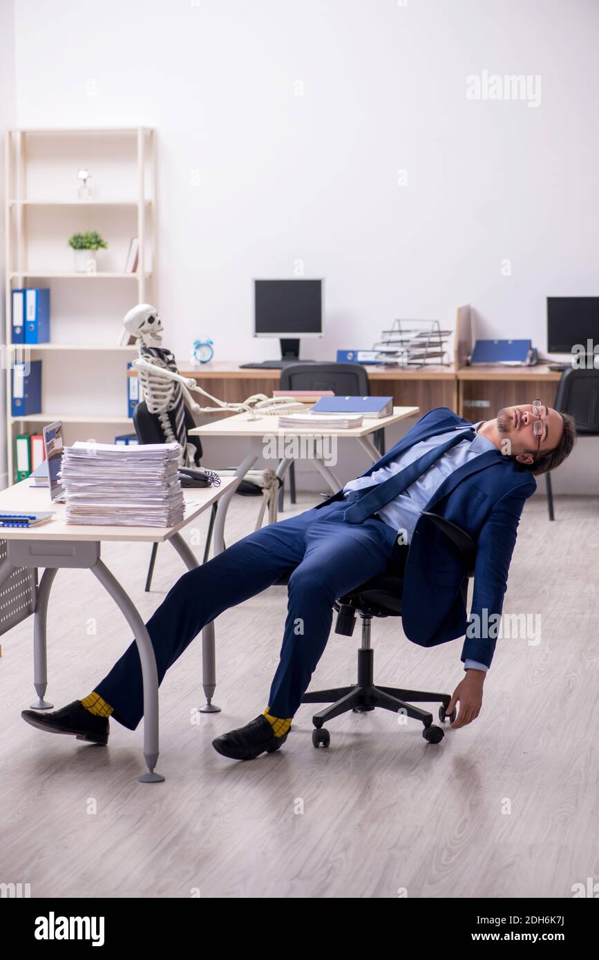 Young male employee with skeletons in the office Stock Photo - Alamy