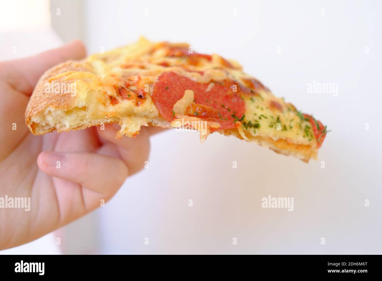 Hand holds a slice of delicious fragrant Italian pizza with pepperoni ...