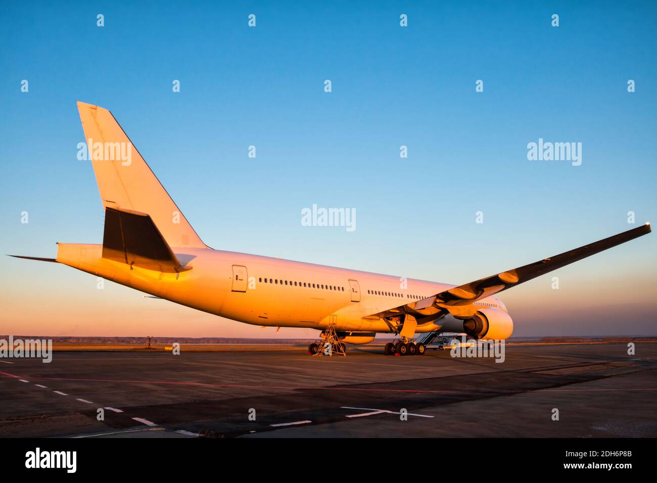 White wide body passenger airplane at the airport apron in the evening ...