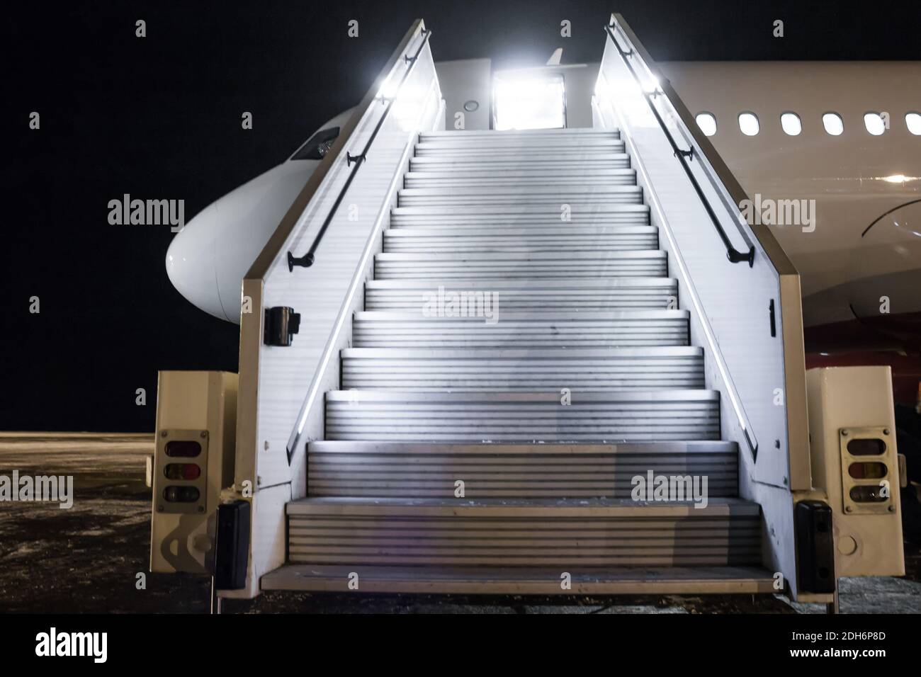 Passenger aircraft with a boarding ramp on the night airport apron ...