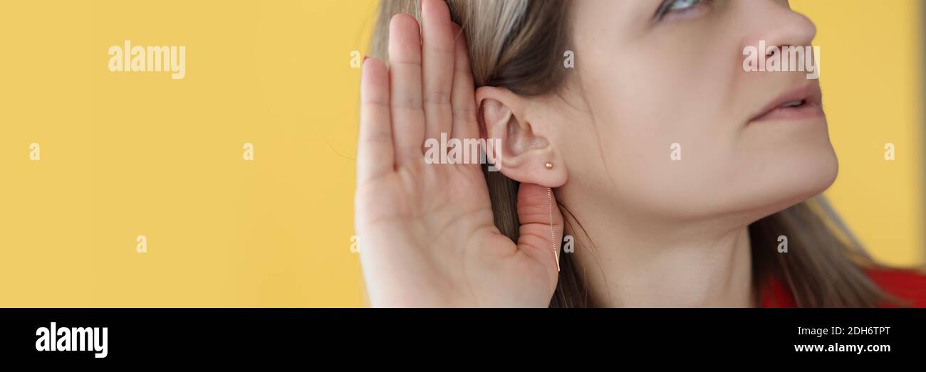 Woman holds her hand near her ear to hear better Stock Photo - Alamy