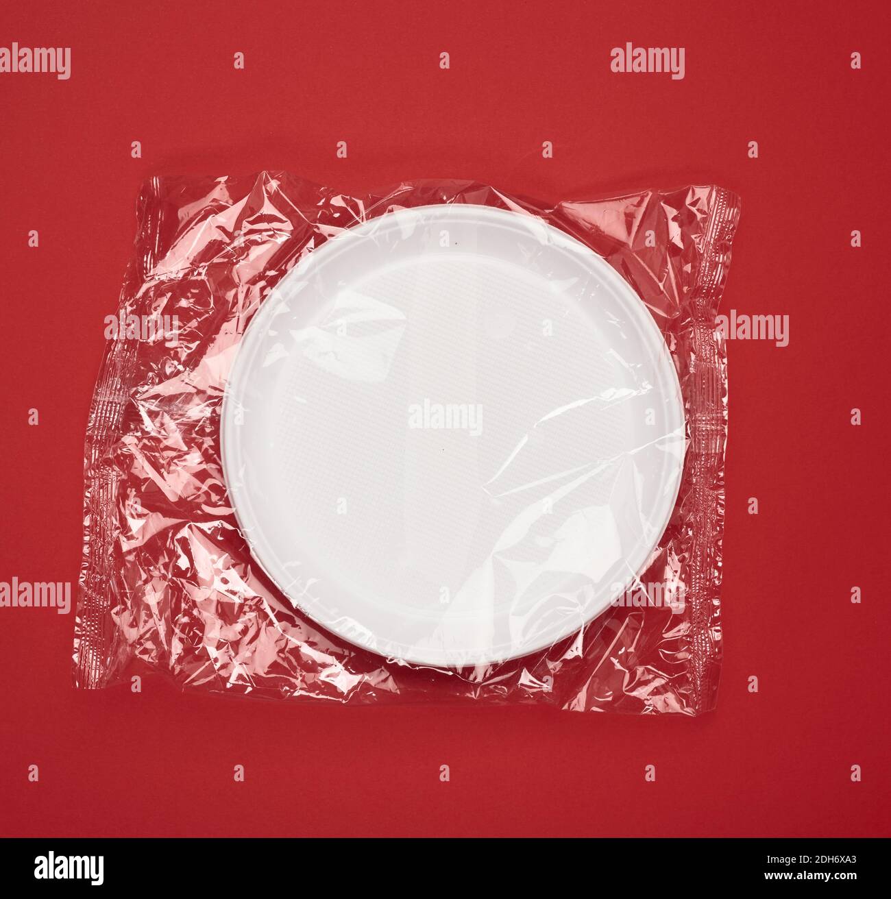 Disposable white plastic plates in transparent plastic packaging on a ...