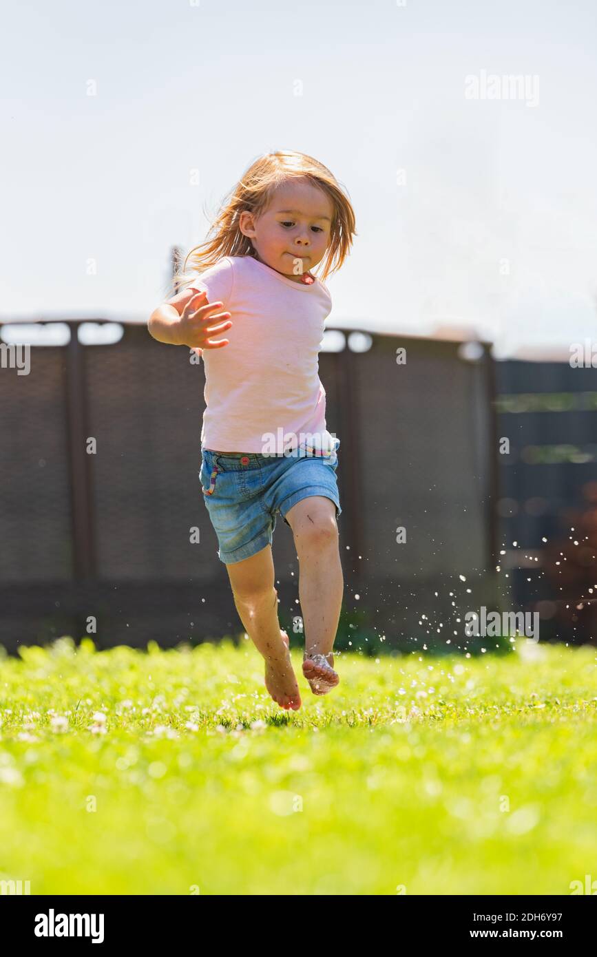 Happy child running through wet lawn splashinh water Stock Photo - Alamy