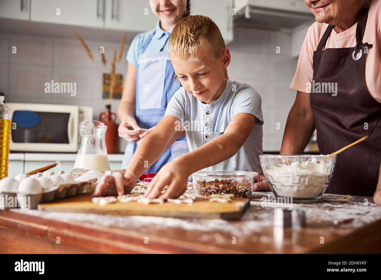 Enthusiastic little chef making cookies with help of his family Stock ...