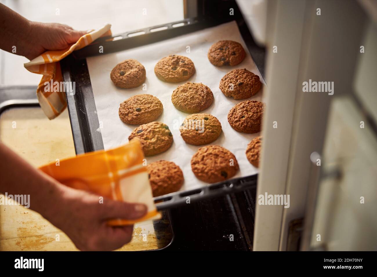 Skilled baker taking pan with cookies out of oven Stock Photo - Alamy