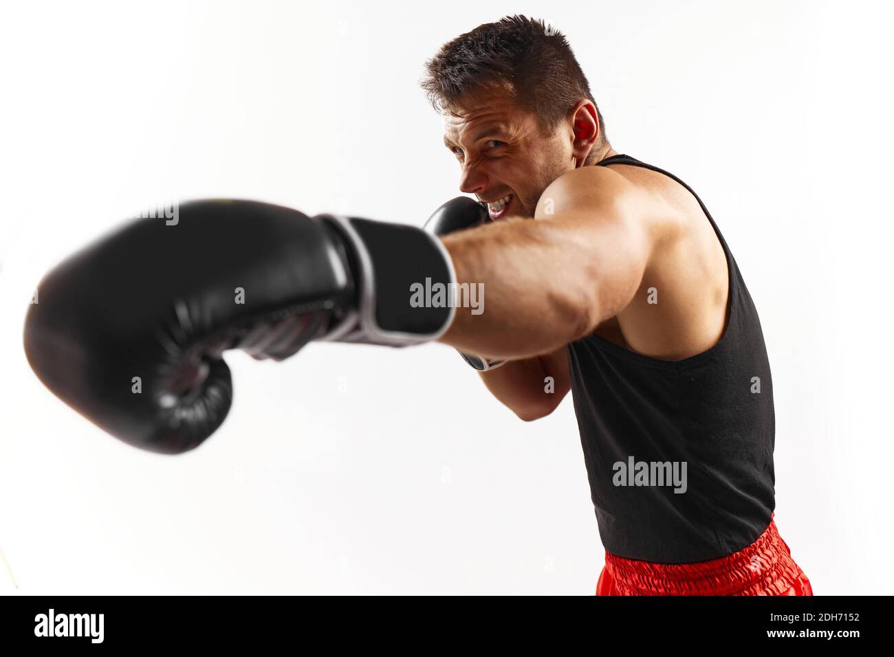 sporty man in black boxing gloves hitting at camera isolated on white ...